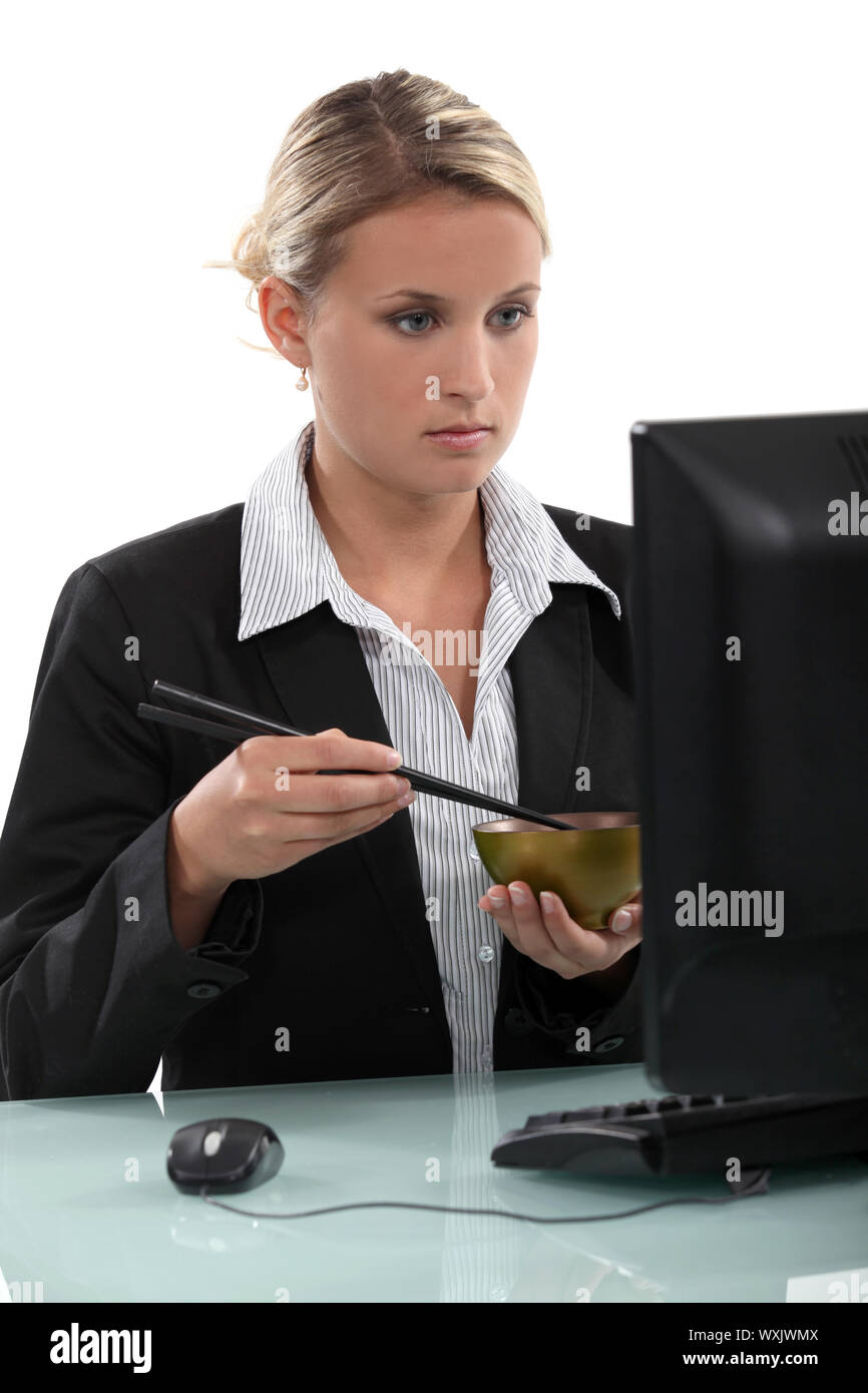 Employee eating at her computer Stock Photo - Alamy