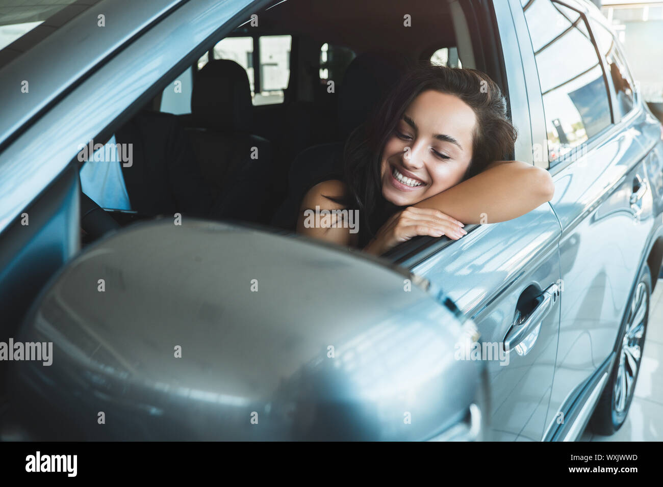 young beautiful woman sitting in new vehicle checking car interior ...
