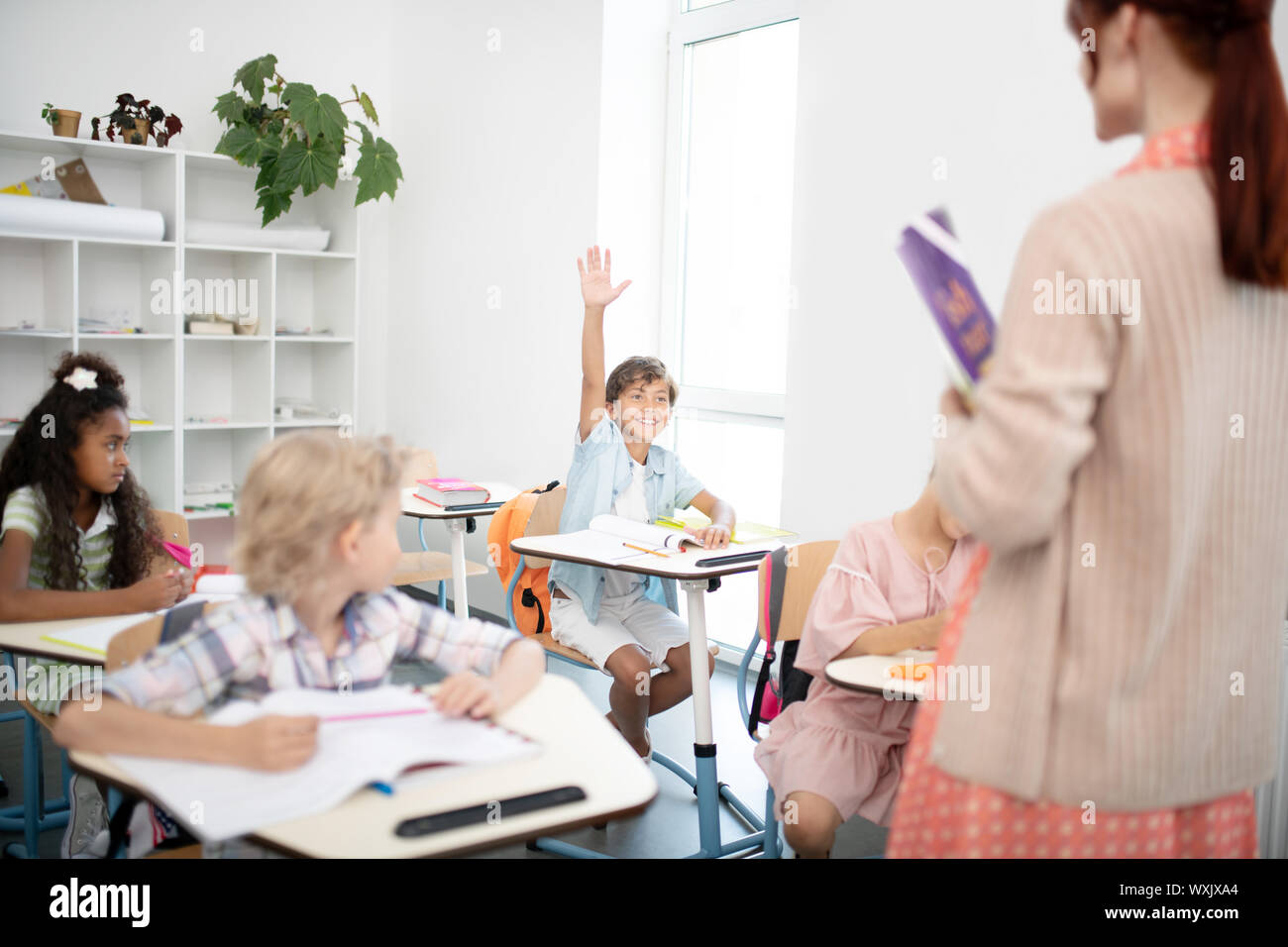 Dark-haired boy being very active during the English lesson Stock Photo ...