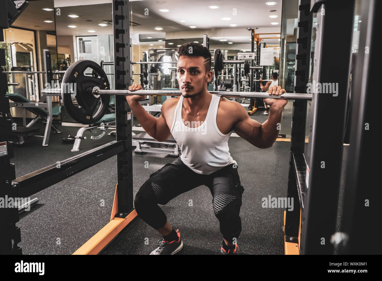Man at the gym. Execute exercise squatting with weight, in gym Stock ...