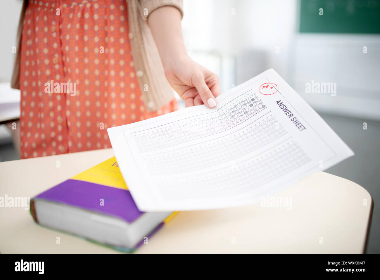 Teacher wearing spotted dress holding answer sheet for tests Stock ...