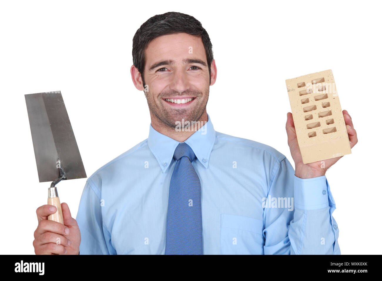 A man in a suit holding a brick and a trowel Stock Photo - Alamy