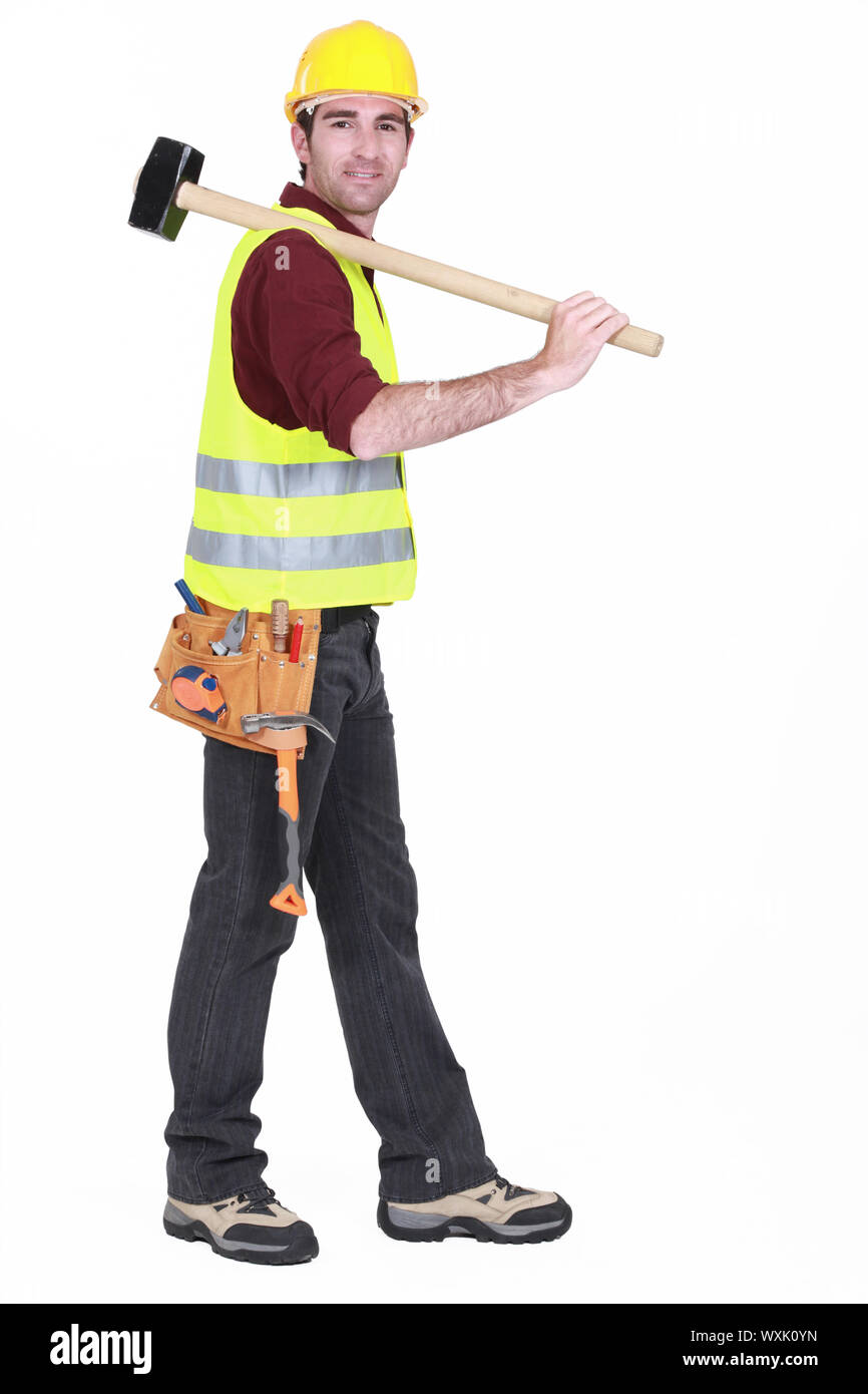 Worker carrying sledge-hammer over shoulder Stock Photo - Alamy