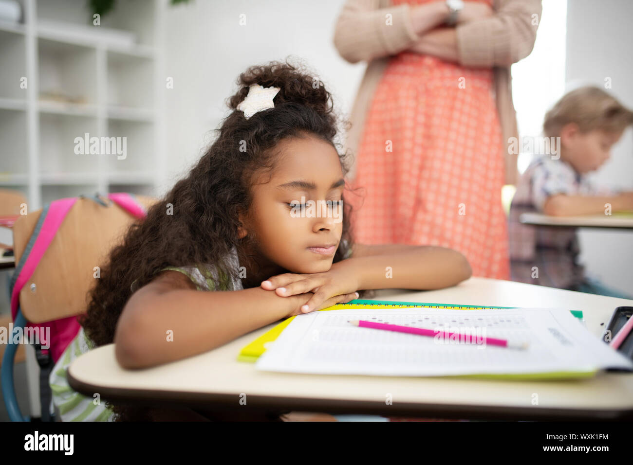 Curly schoolgirl feeling tired after finishing test Stock Photo - Alamy