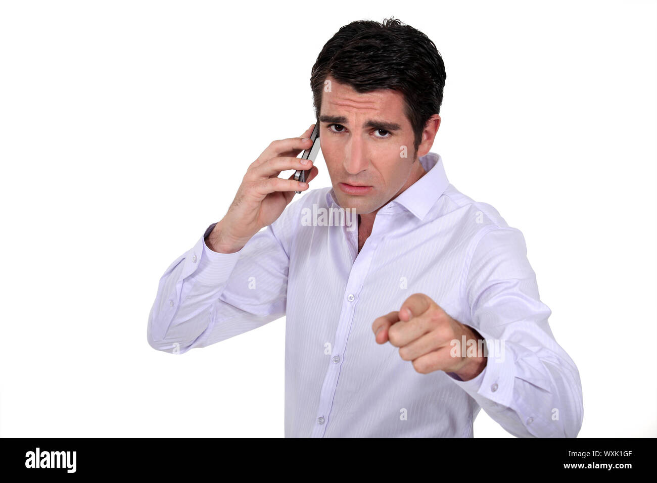 Confident businessman pointing whilst making telephone call Stock Photo ...