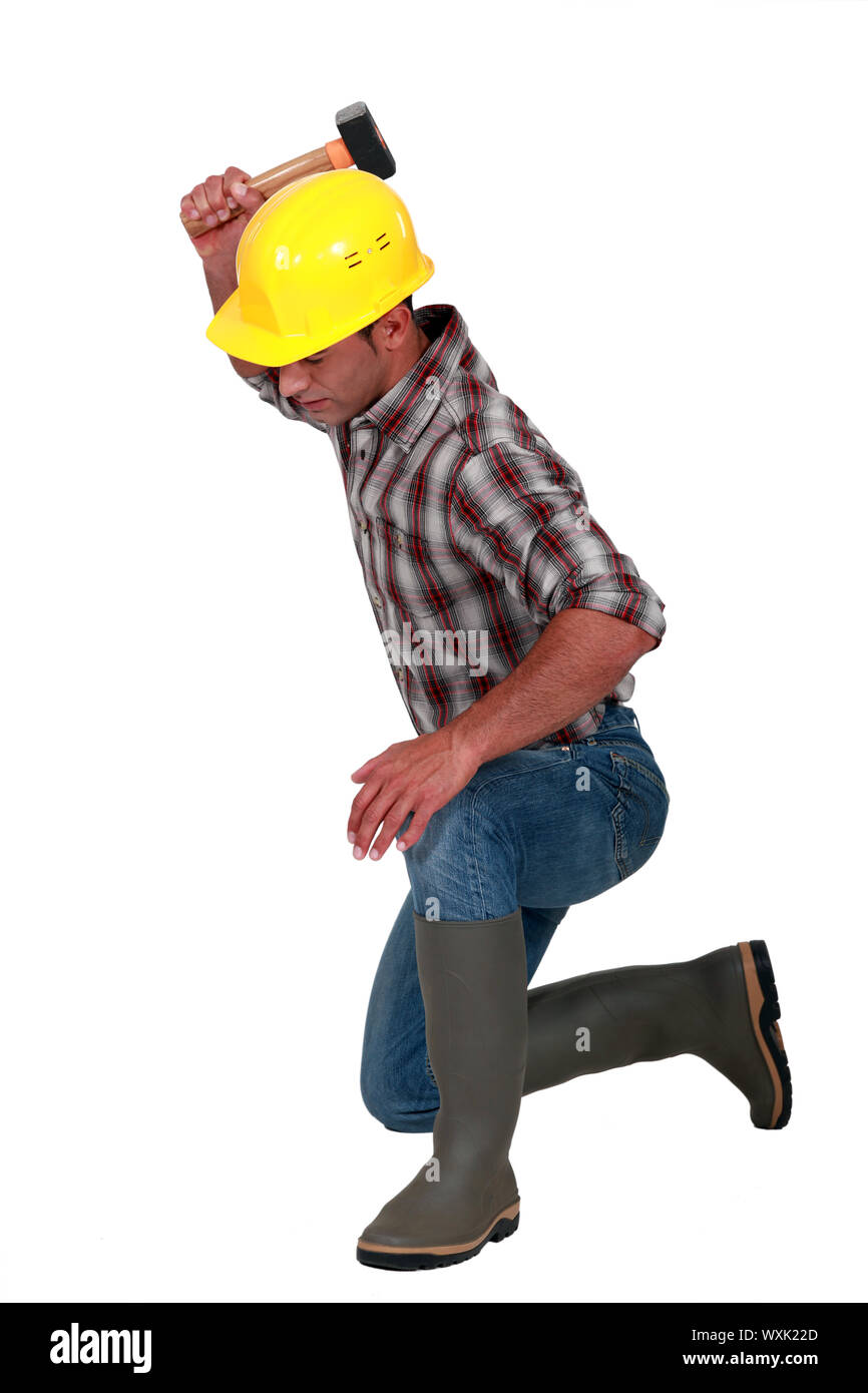 A kneeled carpenter with a hammer Stock Photo - Alamy