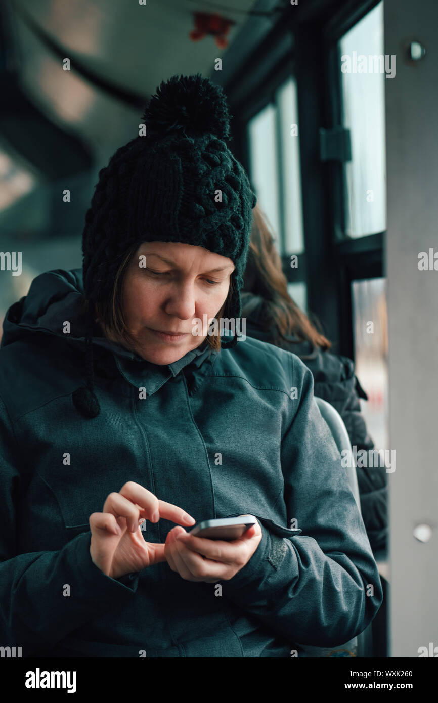 Beautiful adult woman texting on mobile phone in public bus in cold ...