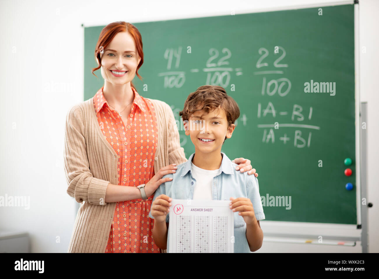 Red-haired teacher smiling and hugging her clever pupil Stock Photo - Alamy