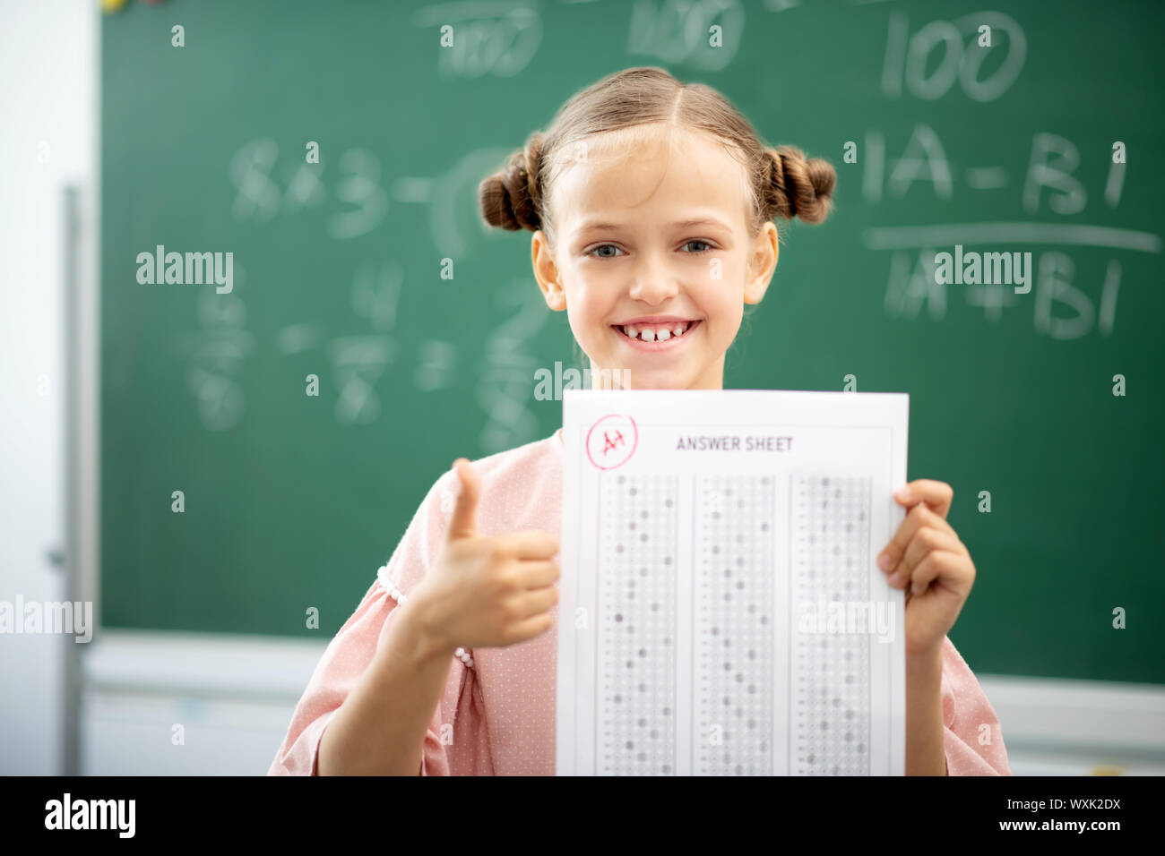 Smiling girl holding her answer sheet with excellent mark Stock Photo ...