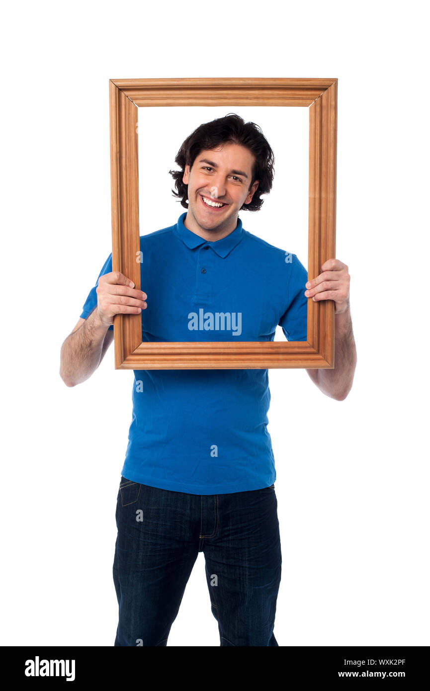 Happy guy looking through empty picture frame Stock Photo - Alamy