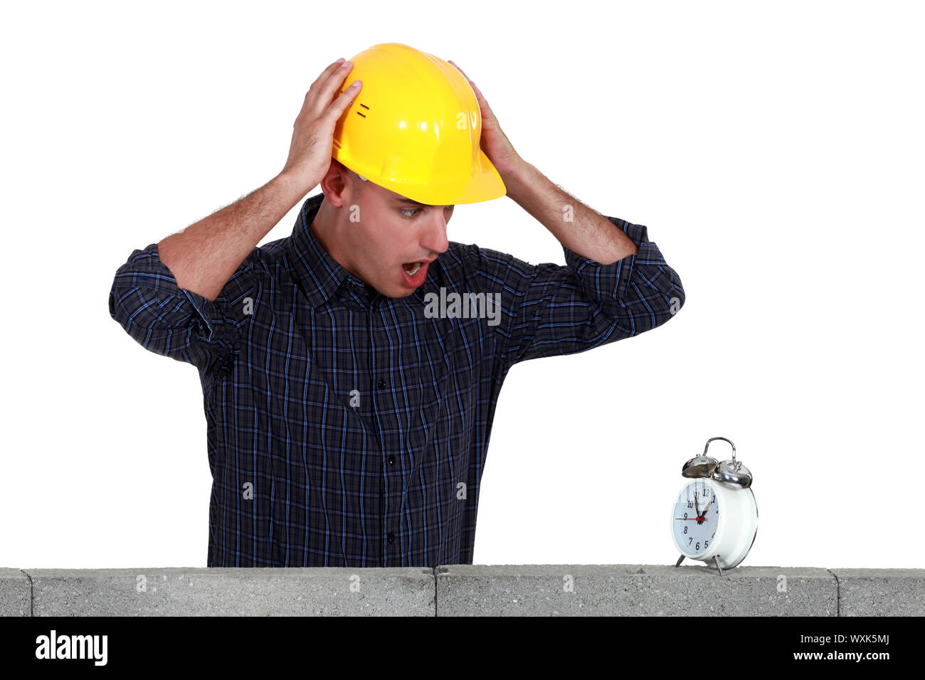 Panicked mason looking at an alarm clock Stock Photo - Alamy
