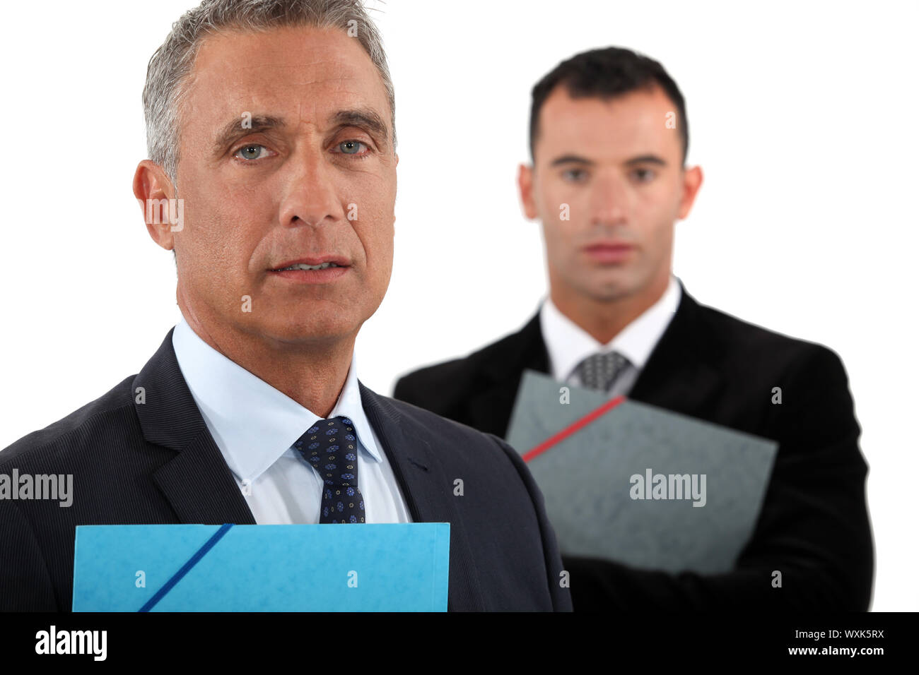 Portrait of a businessman with his assistant trailing behind him Stock ...