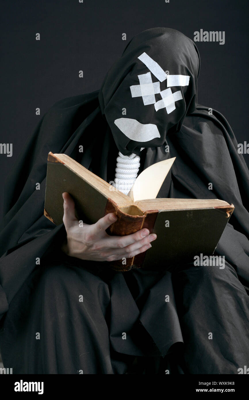 Black mime with rope on neck on black background reading book Stock ...