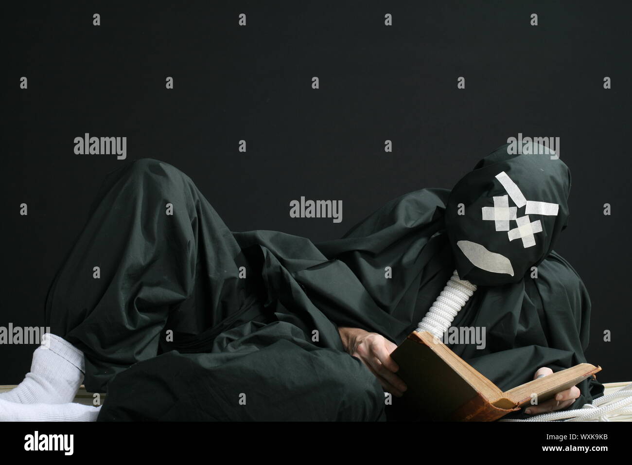Black mime with rope on neck on black background reading book Stock ...