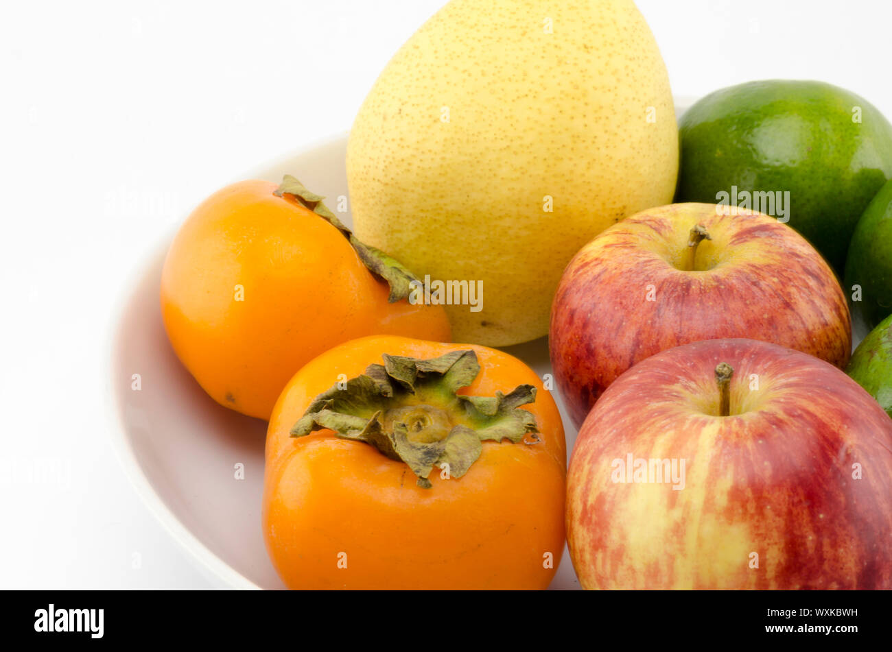 chinese pear apple green orange and persimon on white dish isolated on ...
