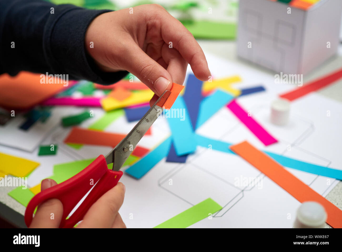 A childrens craft session in front of a teacher cutting up colourful ...