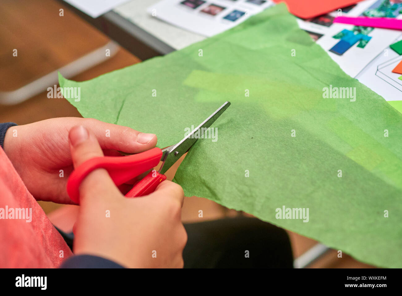 A childrens craft session in front of a teacher cutting up colourful ...