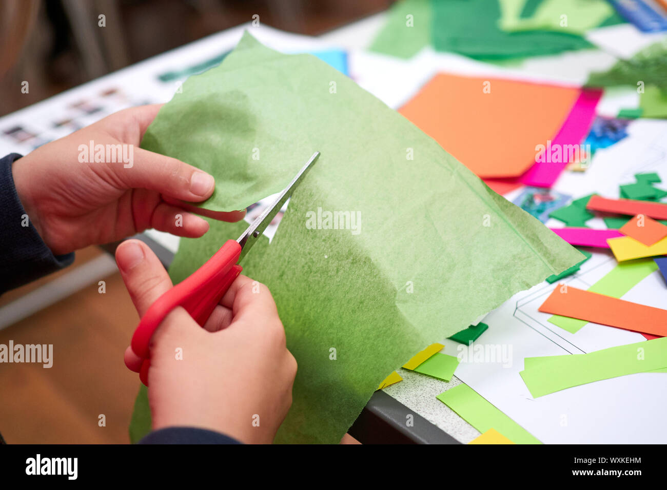 A childrens craft session in front of a teacher cutting up colourful ...