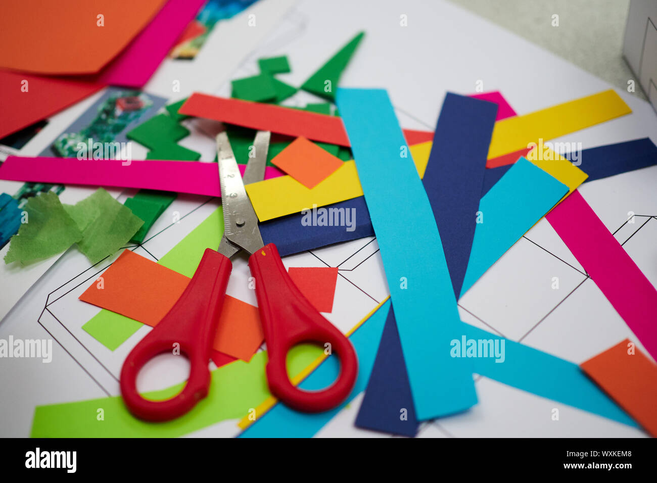 A childrens craft session in front of a teacher cutting up colourful ...