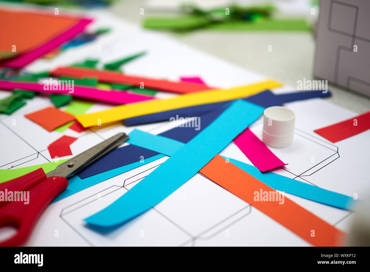 A childrens craft session in front of a teacher cutting up colourful ...