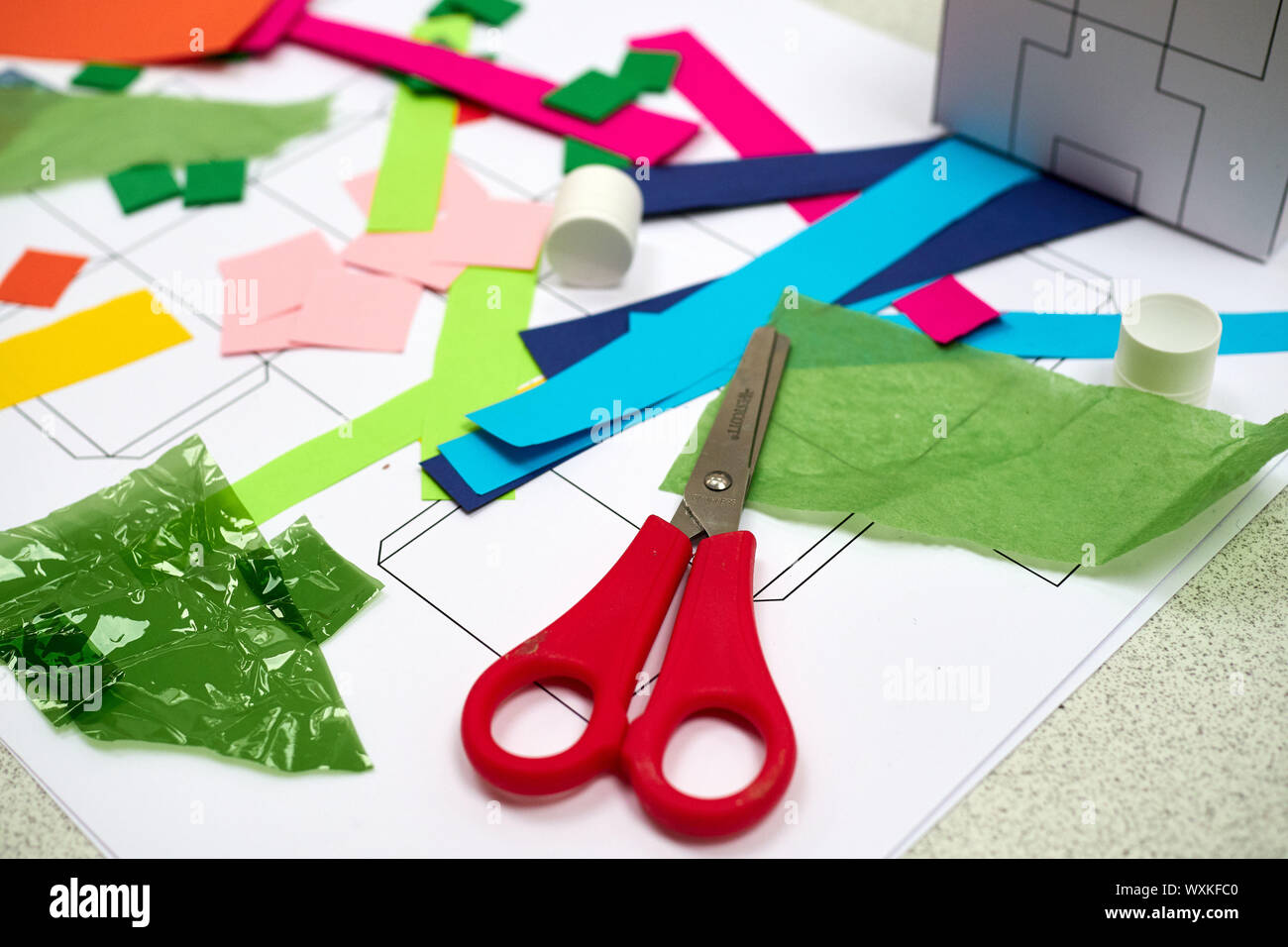 A childrens craft session in front of a teacher cutting up colourful ...