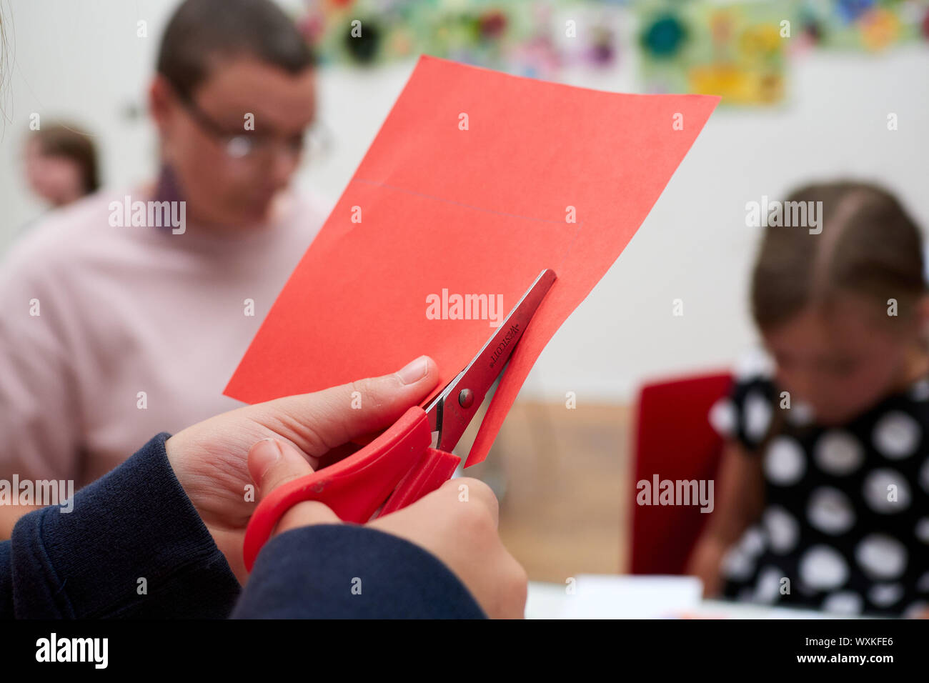 A childrens craft session in front of a teacher cutting up colourful ...