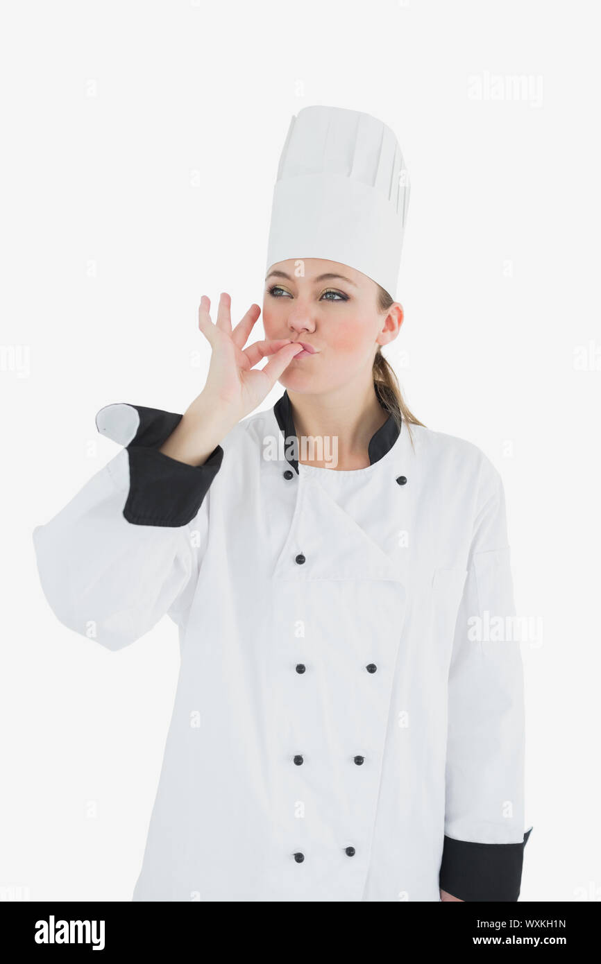 Female chef kissing her fingers while looking away over white ...