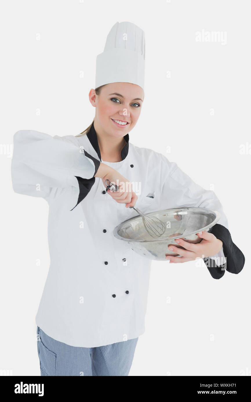 Portrait of happy female chef holding wire whisk and mixing bowl ...