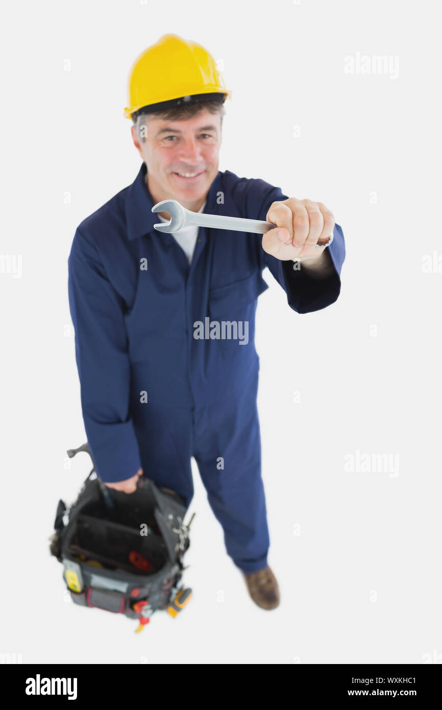 Portrait of technician with wrench carrying tool bag over white ...