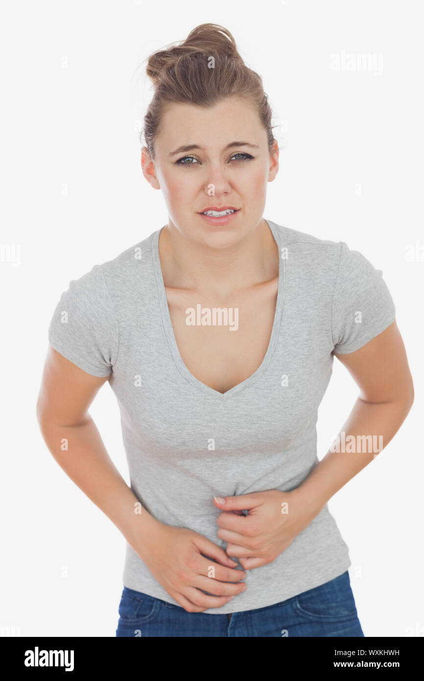 Portrait of unhappy young woman suffering from stomach pain against ...
