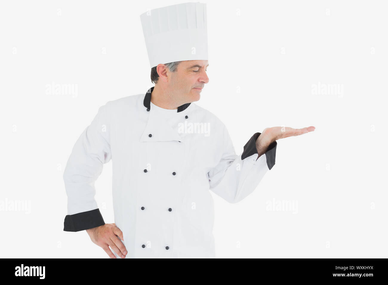 Mature male chef looking at invisible product over white background ...