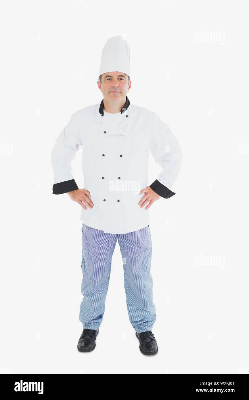 Full length of confident chef standing with arms akimbo against white ...