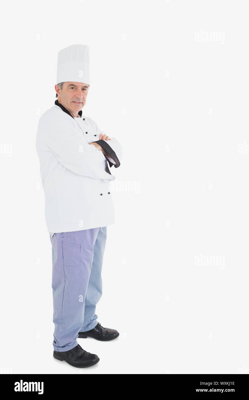 Portrait of mature male chef with arms crossed standing over white ...