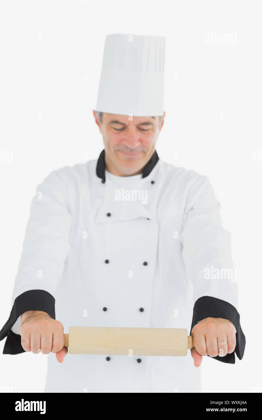 Mature man in chef uniform using rolling pin over white background ...