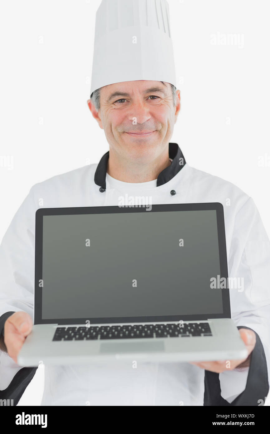Portrait of happy male chef presenting laptop against white background ...