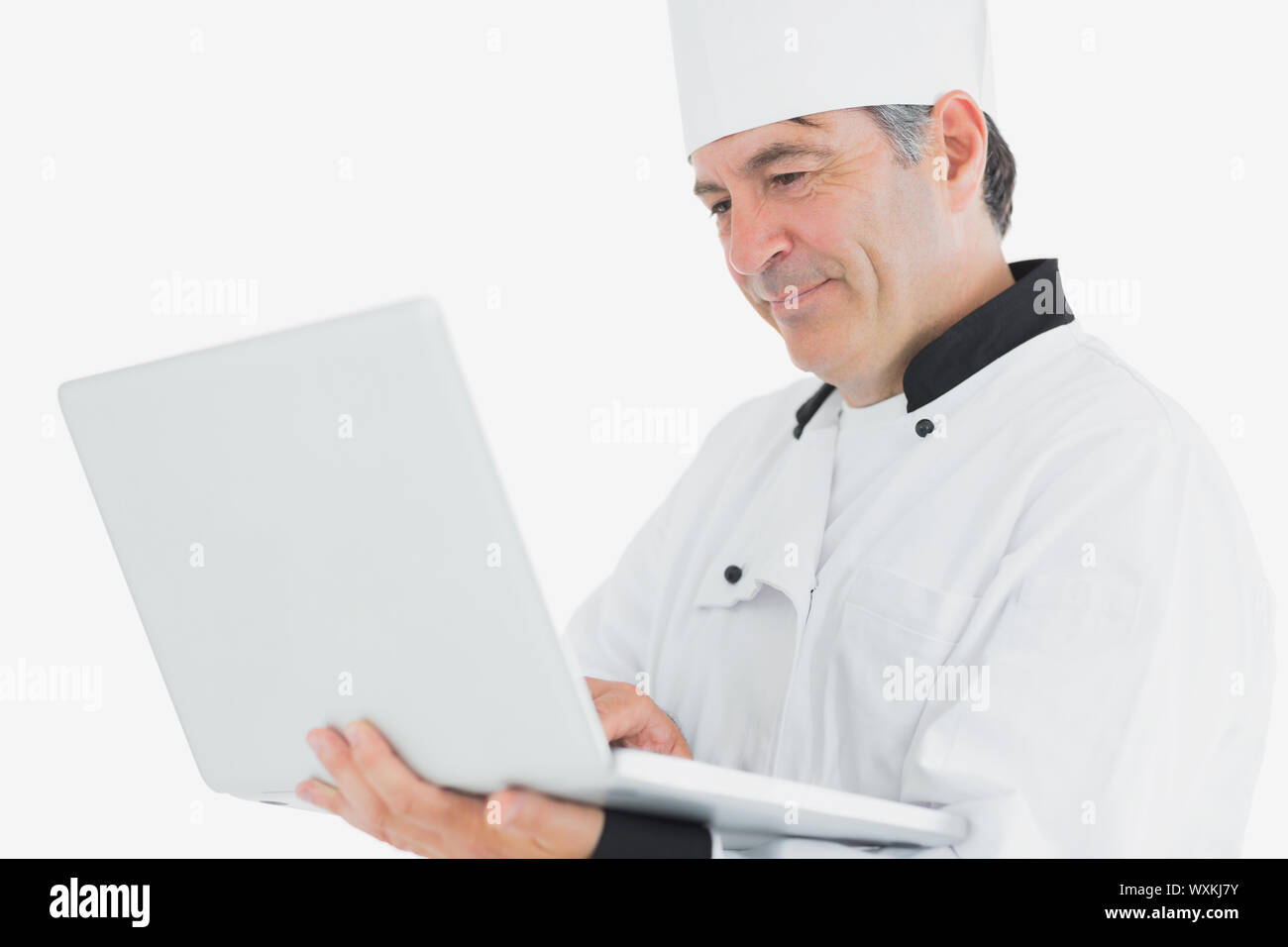 Male chef using laptop smiling against white background Stock Photo - Alamy