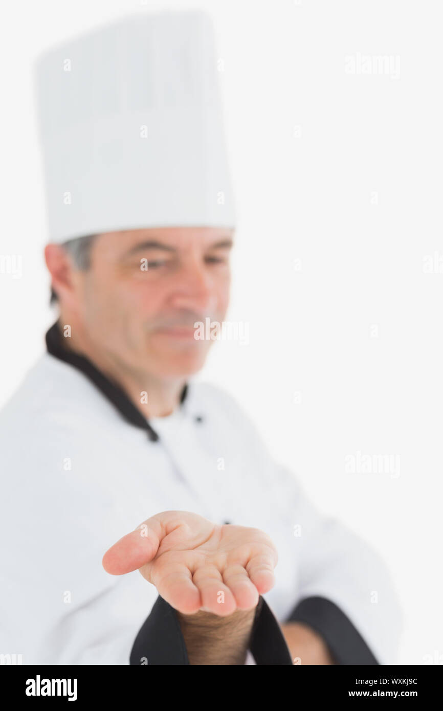 Male chef displaying an invisible product standing against white ...