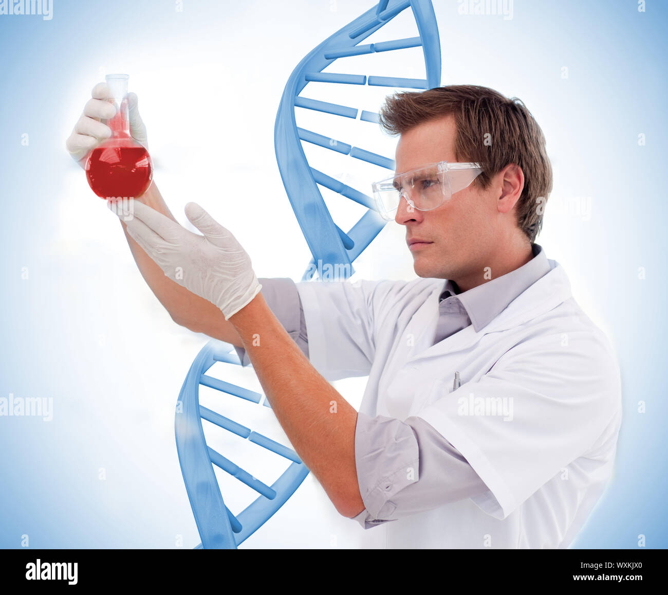 Handsome scientist looking at beaker of blood against DNA background ...