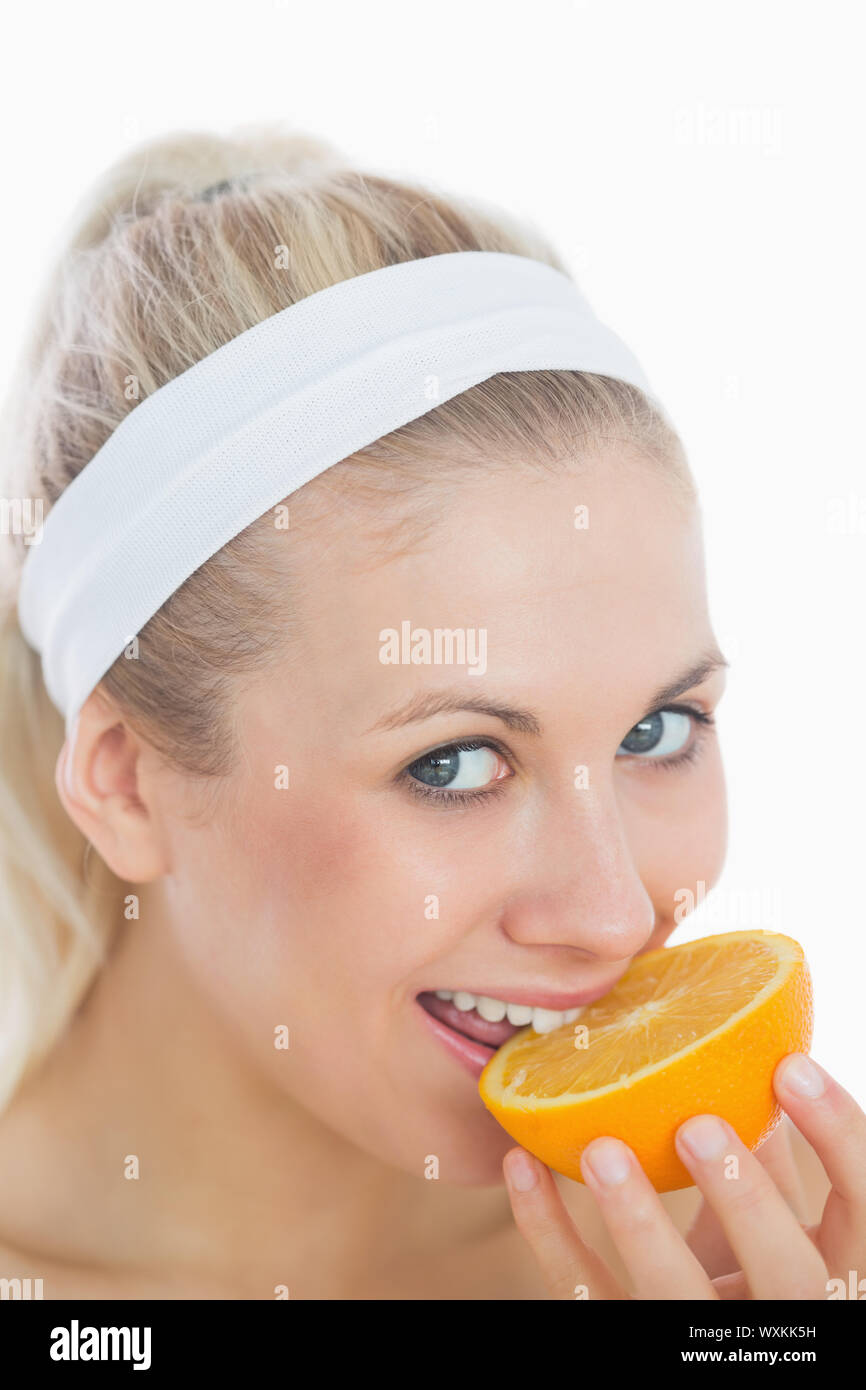 Closeup portrait of beautiful young woman biting slice of orange over ...