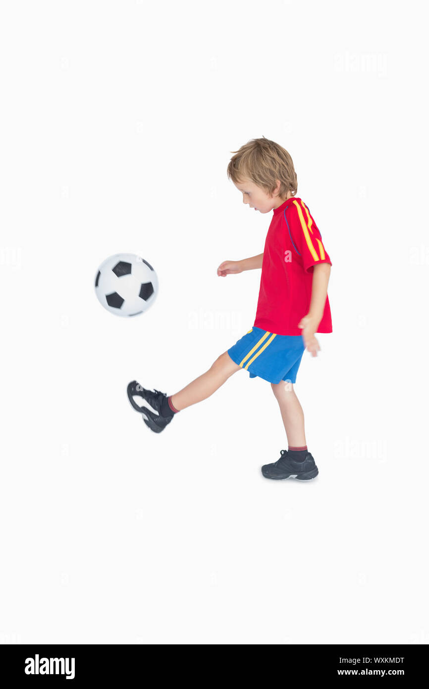 Side view of little boy kicking football over white background Stock ...