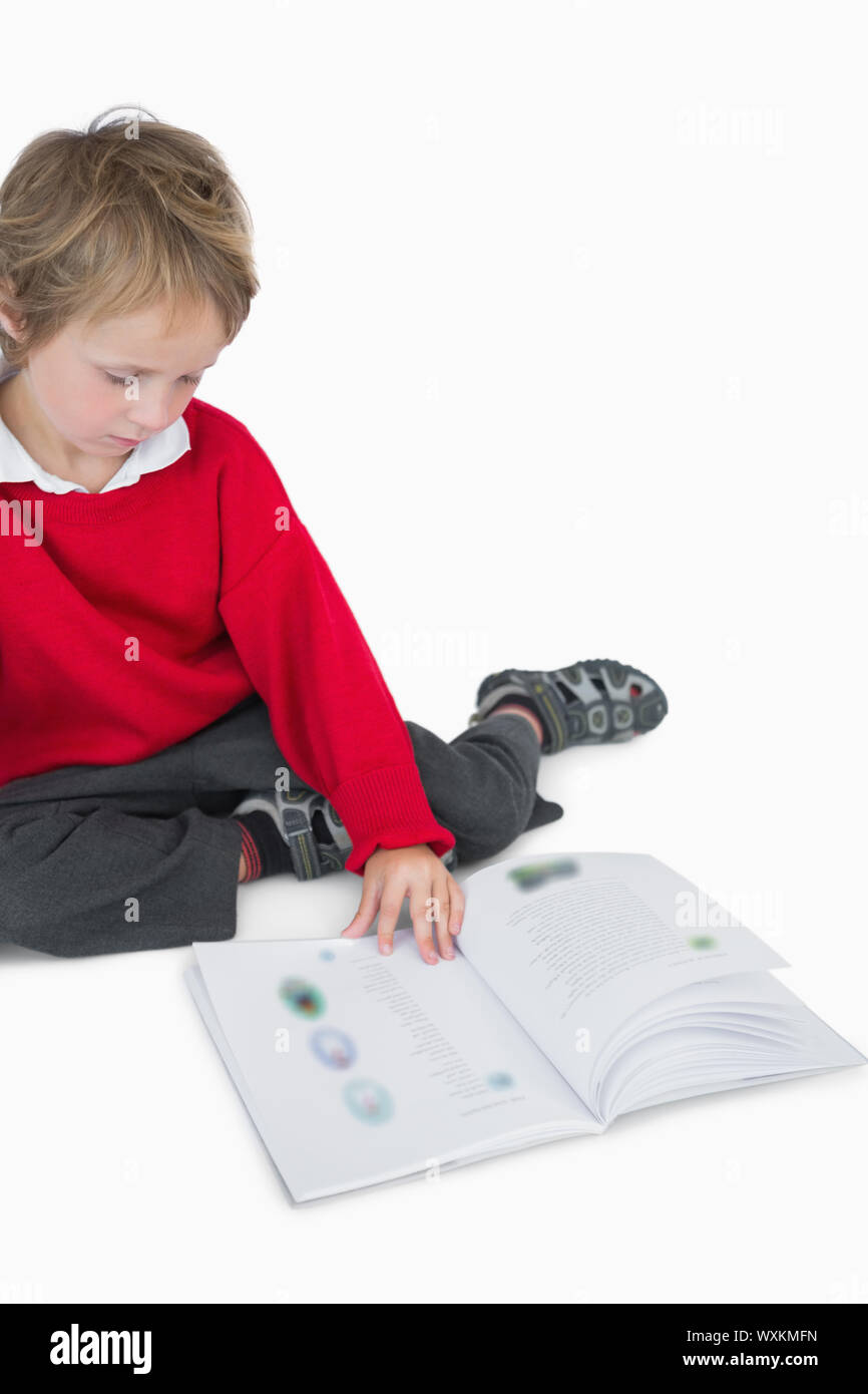 Little boy sitting and reading book over white background Stock Photo ...