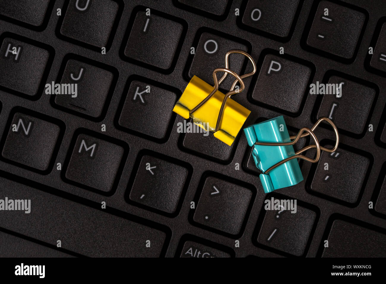 Color paper clips on the black computer keyboard Stock Photo - Alamy