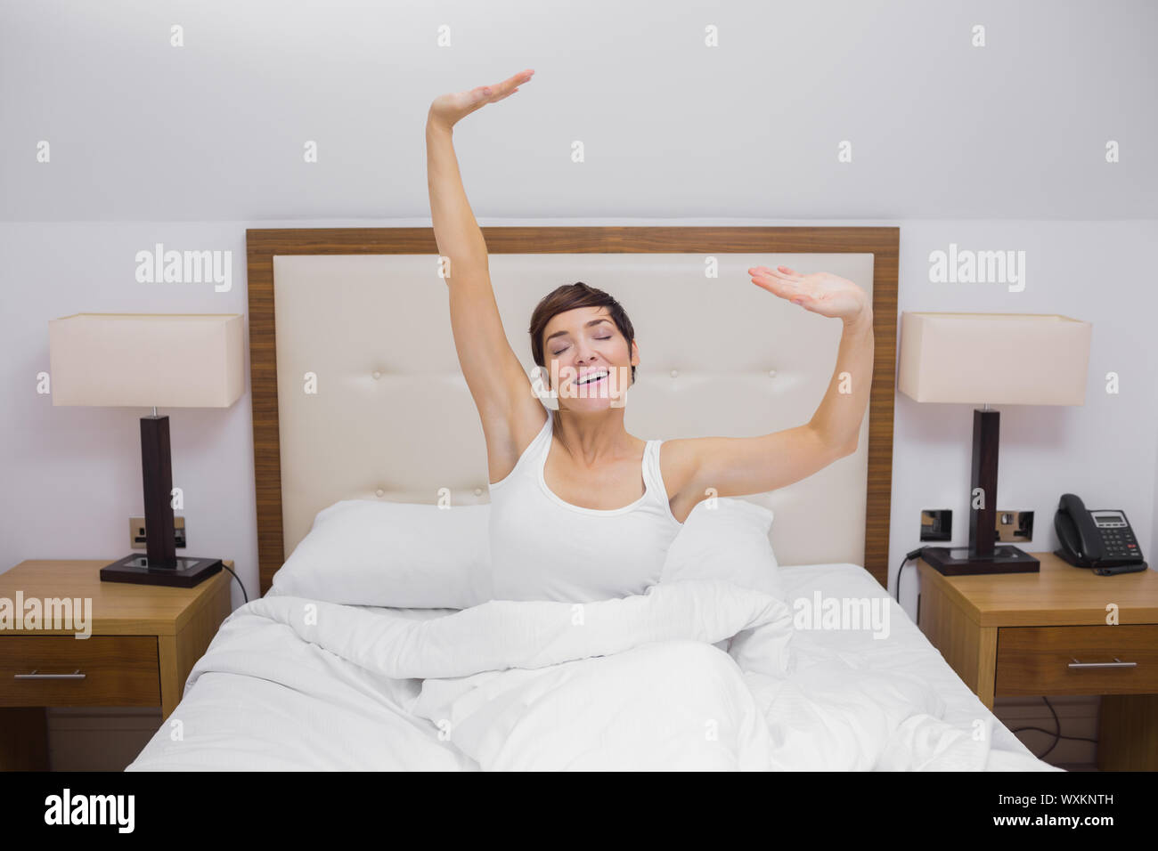 Pretty girl stretching in bed in a hotel room Stock Photo - Alamy