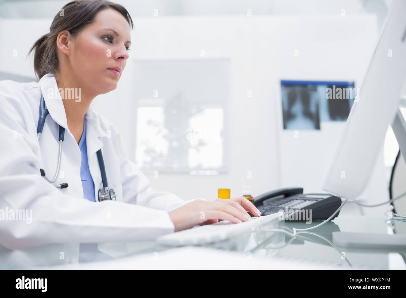 Side view of young female doctor using computer at clinic Stock Photo ...