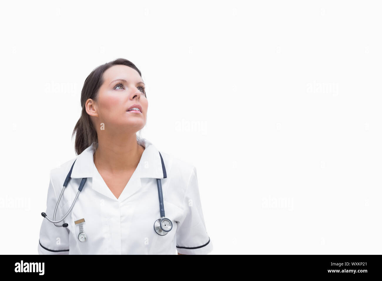 Nurse looking up thoughtfully against white background Stock Photo - Alamy