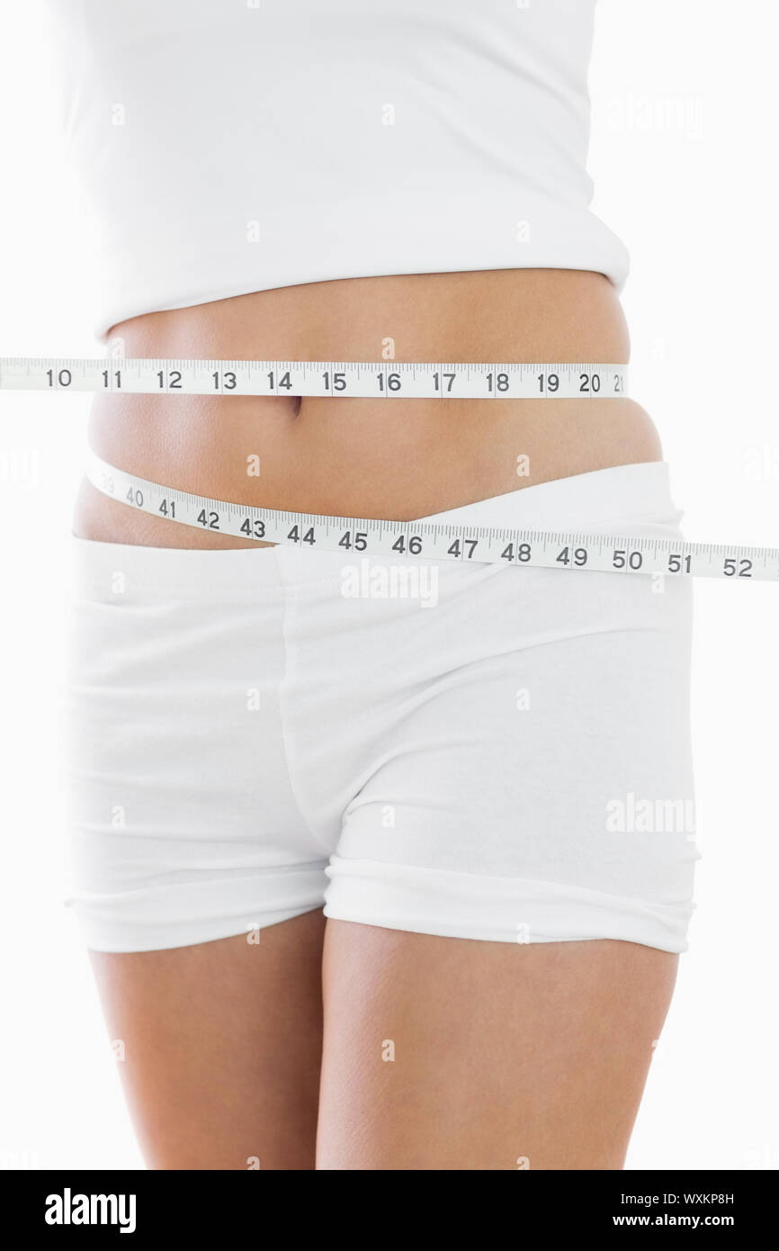 Closeup midsection of woman measuring waist over white background Stock ...