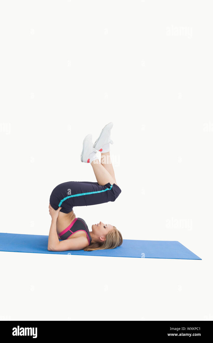 Side view of young woman in the shoulder stand position on yoga mat ...