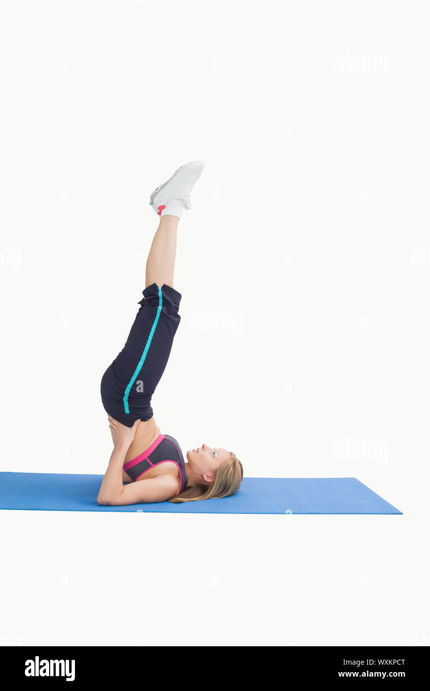 Side view of young woman in the shoulder stand position on yoga mat ...