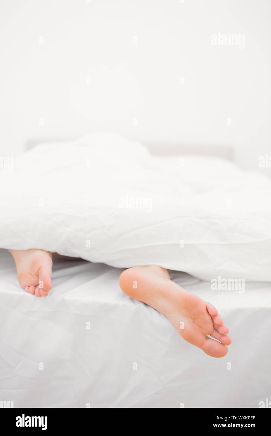 Womans feet sticking out of blanket on bed at home Stock Photo - Alamy