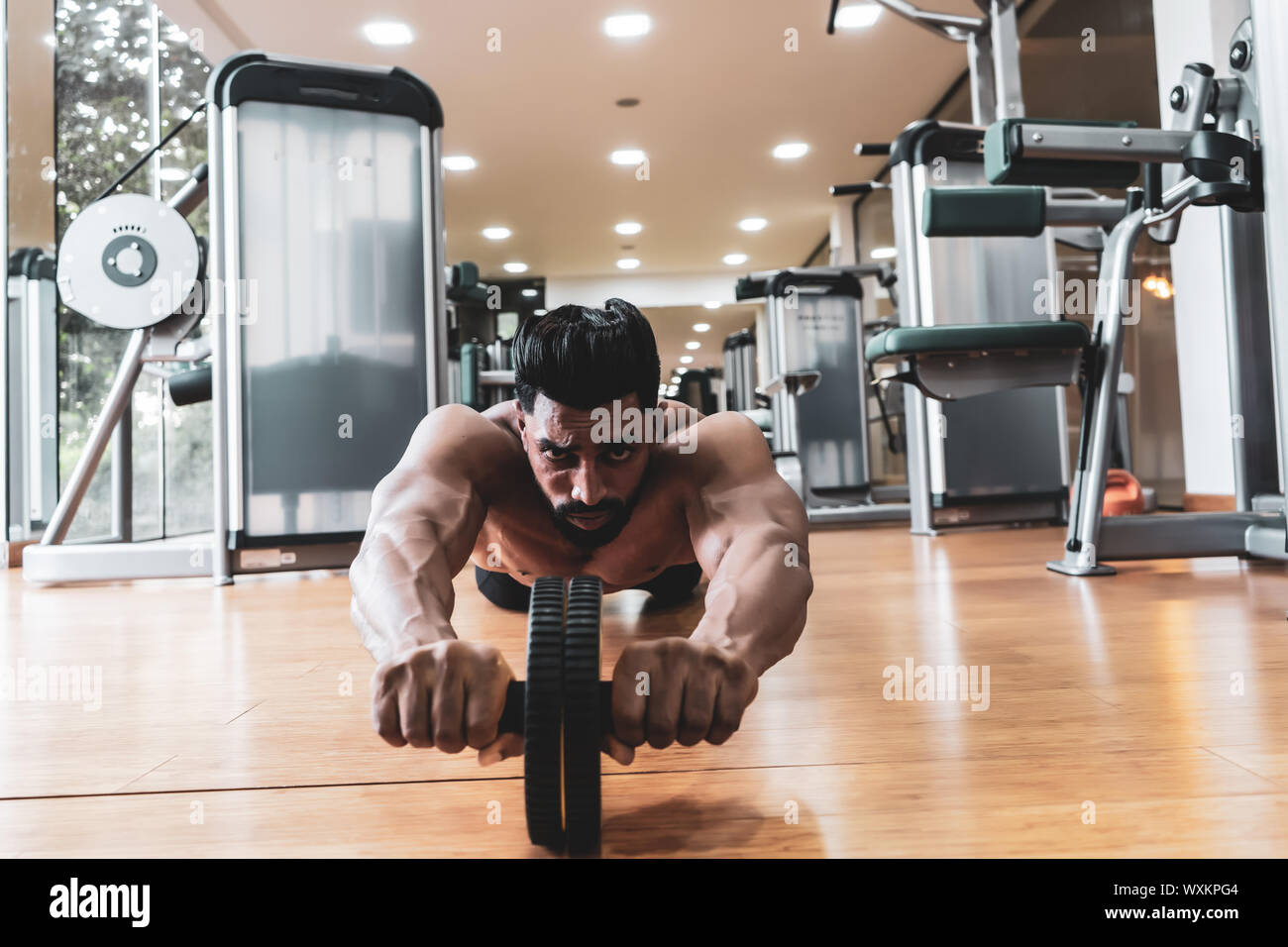 Athlete sporty man doing exercise with abs roller wheel to strengthen ...